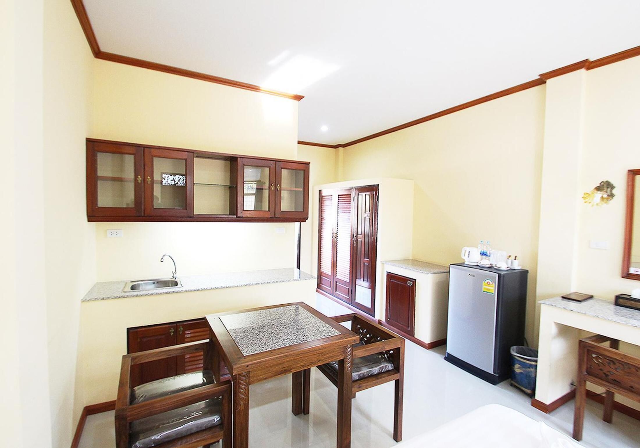 Uma cozinha compacta com armários de madeira, geladeira e um espaço de refeições com mesa e cadeiras.