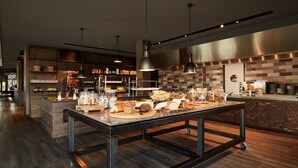 Cozinha moderna com bancada de mármore, luminárias pendentes e diversos alimentos expostos.