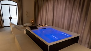 Um spa moderno com uma piscina grande e aquecida, uma área de estar e uma vista através de uma janela ampla.