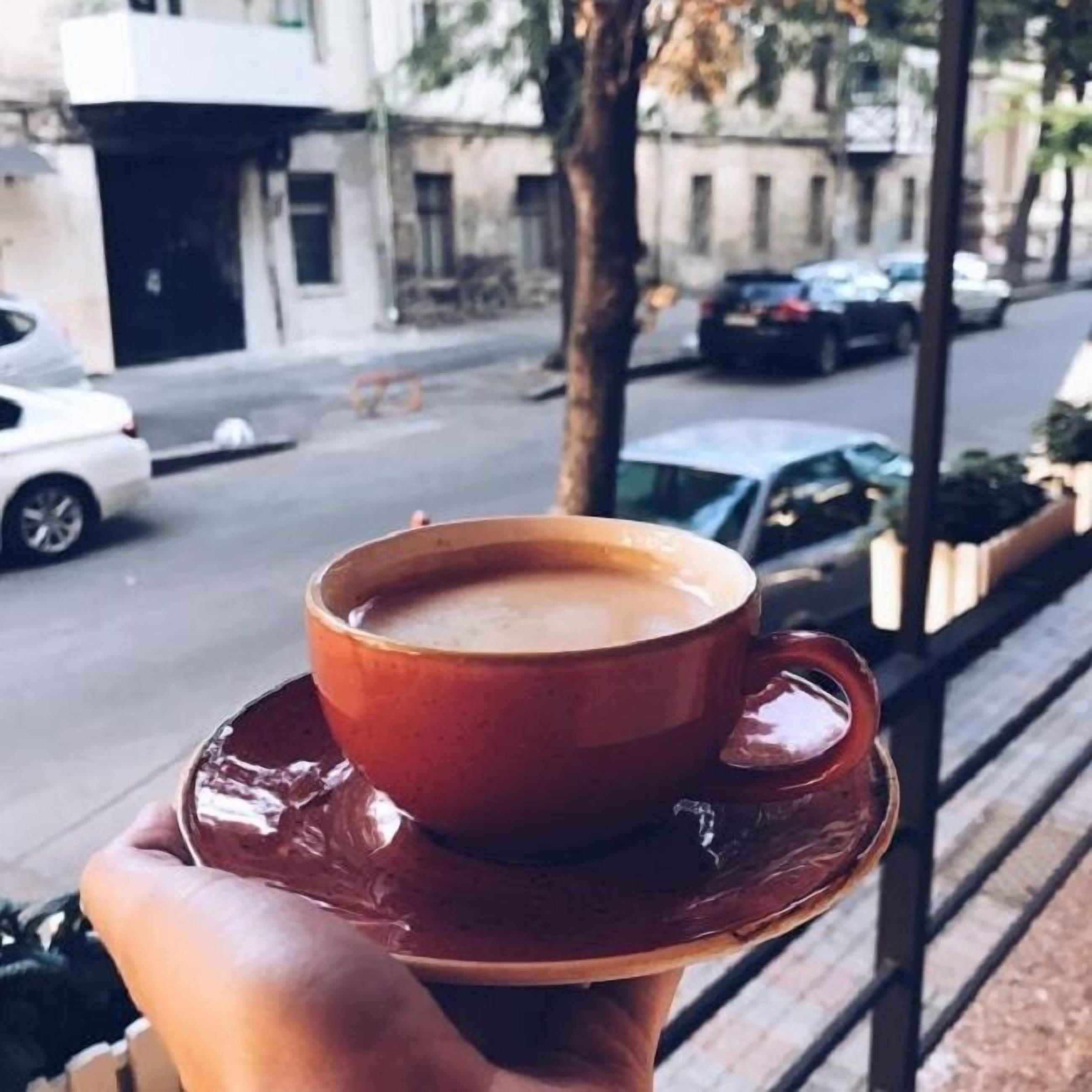 Uma mão segurando uma xícara de café em um pires.