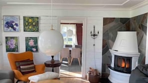 Uma sala de estar com lareira, espaço para refeições e obras de arte nas paredes.