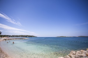 Perto da praia, areia branca, espreguiçadeiras, guarda-sóis