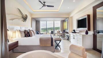 Quarto de hotel moderno com uma cama grande, área de estar, televisão e varanda com vista.