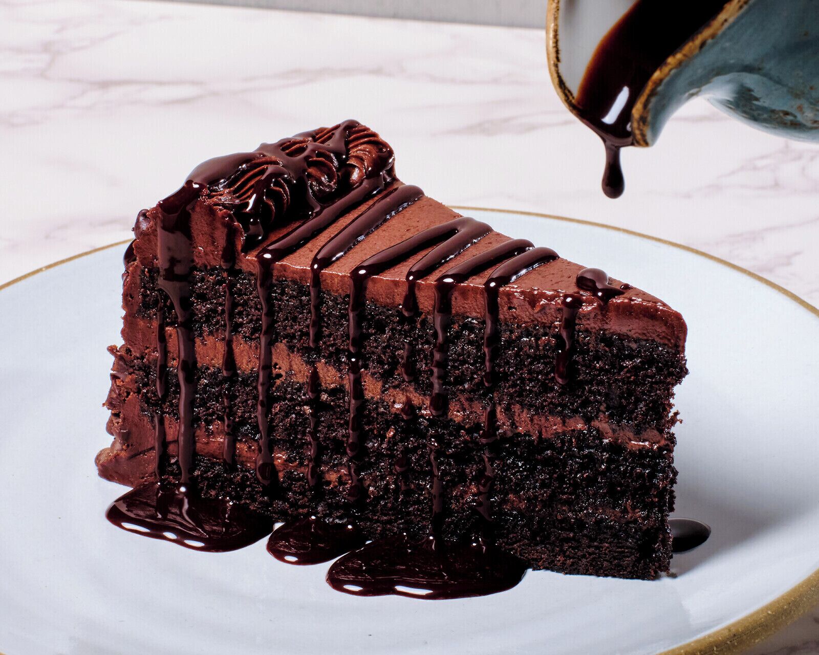 Uma fatia de bolo de chocolate com calda de chocolate em um prato.