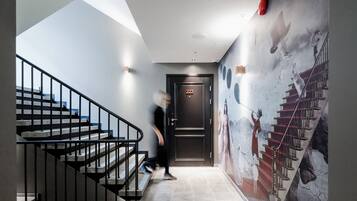 Um interior moderno com uma escada, uma porta com o número 222 e um mural na parede.