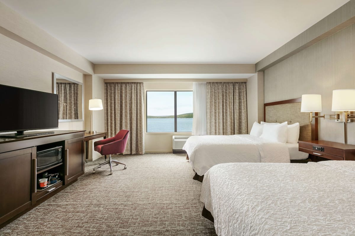 Quarto de hotel com duas camas, televisão, escrivaninha e uma cadeira.