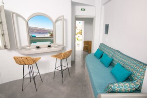 Quarto com sofá, duas cadeiras de vime, vista para a água e porta que dá para outro espaço.