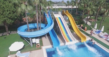 Parque aquático com várias piscinas escorregas e áreas de lazer com guarda-sóis.