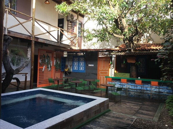 Pátio com piscina, área de estar externa e uma árvore.
