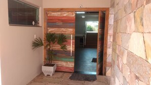 Um corredor com uma porta de madeira colorida, um vaso de planta e uma parede de pedra.