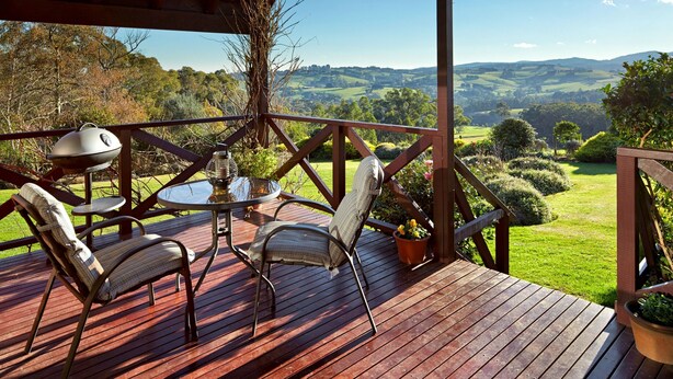 Um deck de madeira com mesa e cadeiras, com vista para uma paisagem deslumbrante.