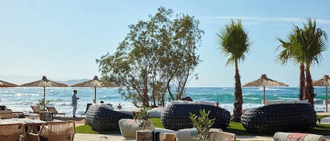 Um restaurante à beira-mar com área externa, mesas e cadeiras, com vista para o oceano.