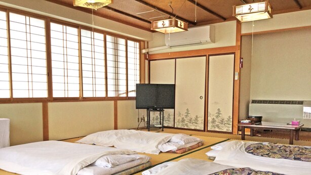 Um quarto japonês tradicional, com tatames, televisão e portas deslizantes.