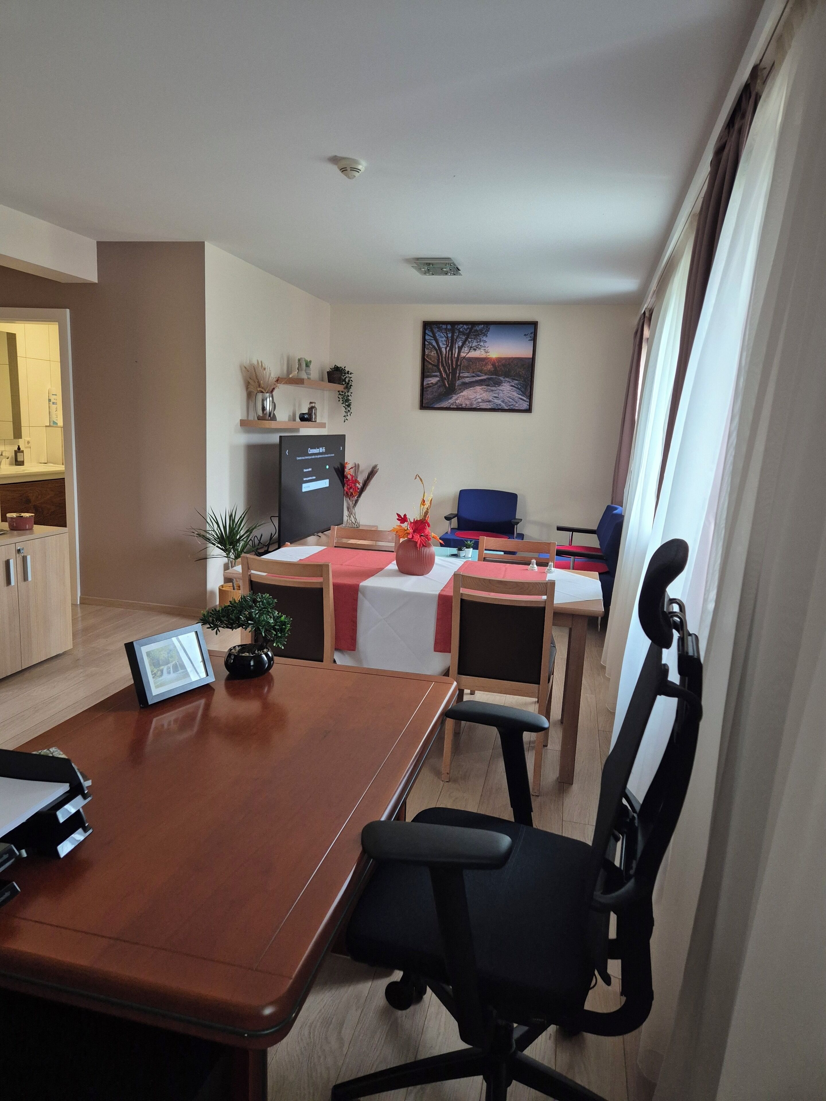 Uma sala de estar moderna com área de jantar, televisão e um quadro na parede.