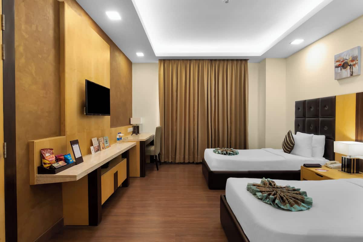 Quarto de hotel com duas camas, uma mesa de trabalho, televisão de tela plana, minibar e uma janela grande com cortinas.
