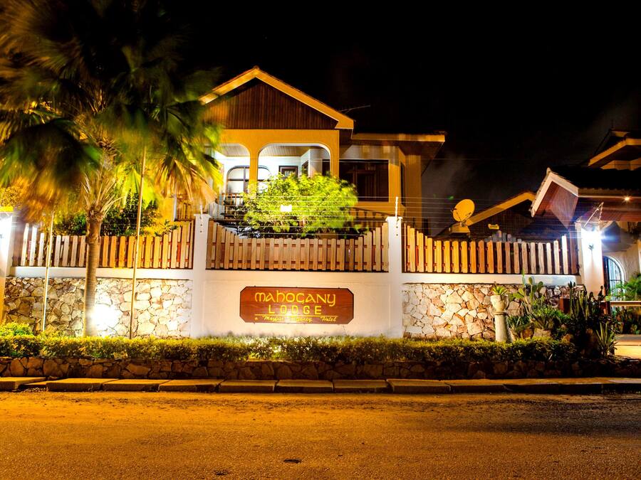 Um edifício com fachada de pedra, cerca de madeira e uma placa com a inscrição "Mahocany Lodge".