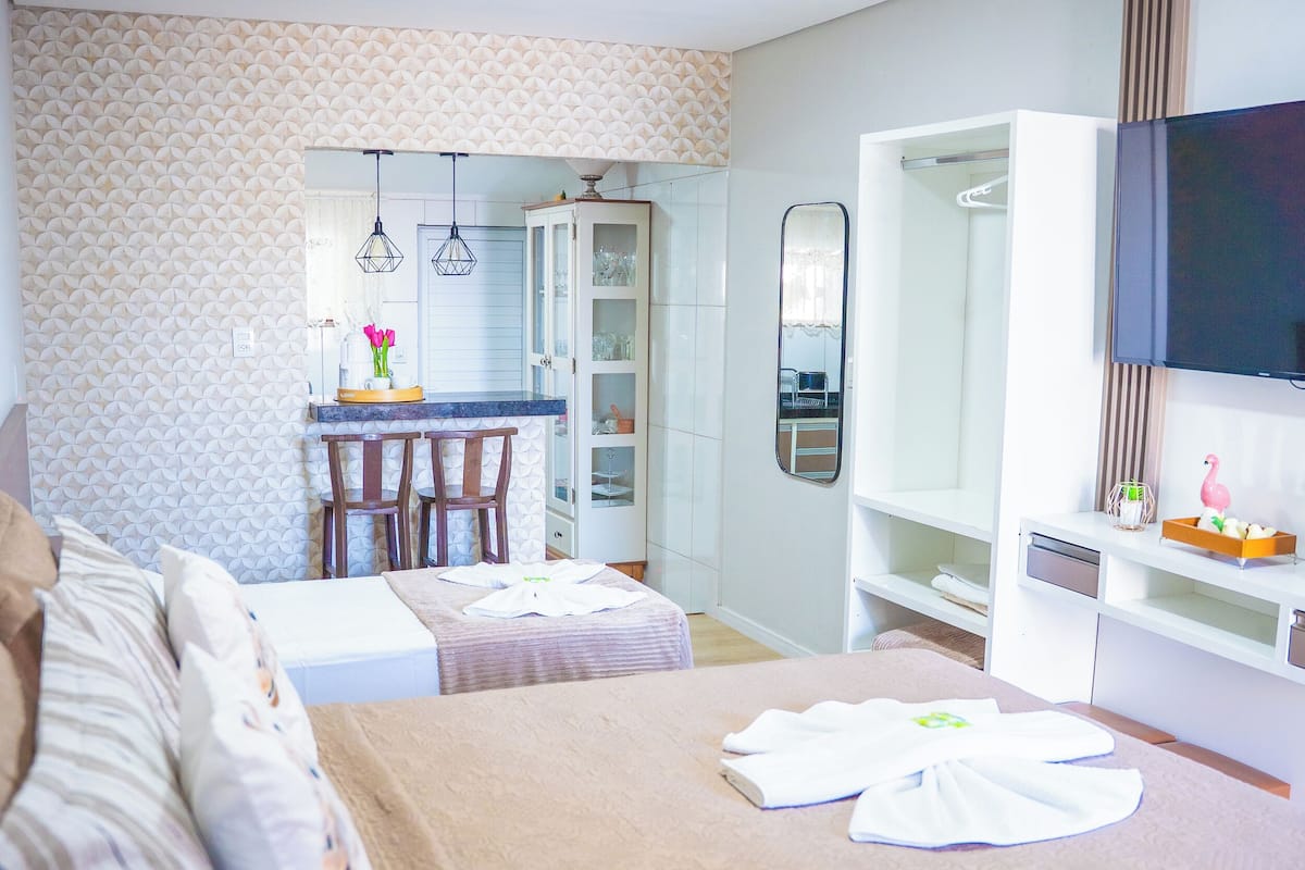 Quarto de hotel com uma cama, uma mesa e uma televisão.