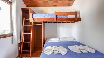 Uma cama beliche com escada, um cobre-leito azul e toalhas no chão.