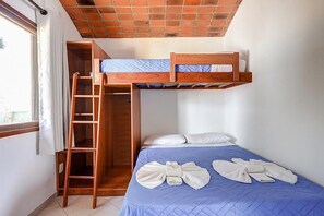Uma cama beliche com escada, um cobre-leito azul e toalhas no chão.
