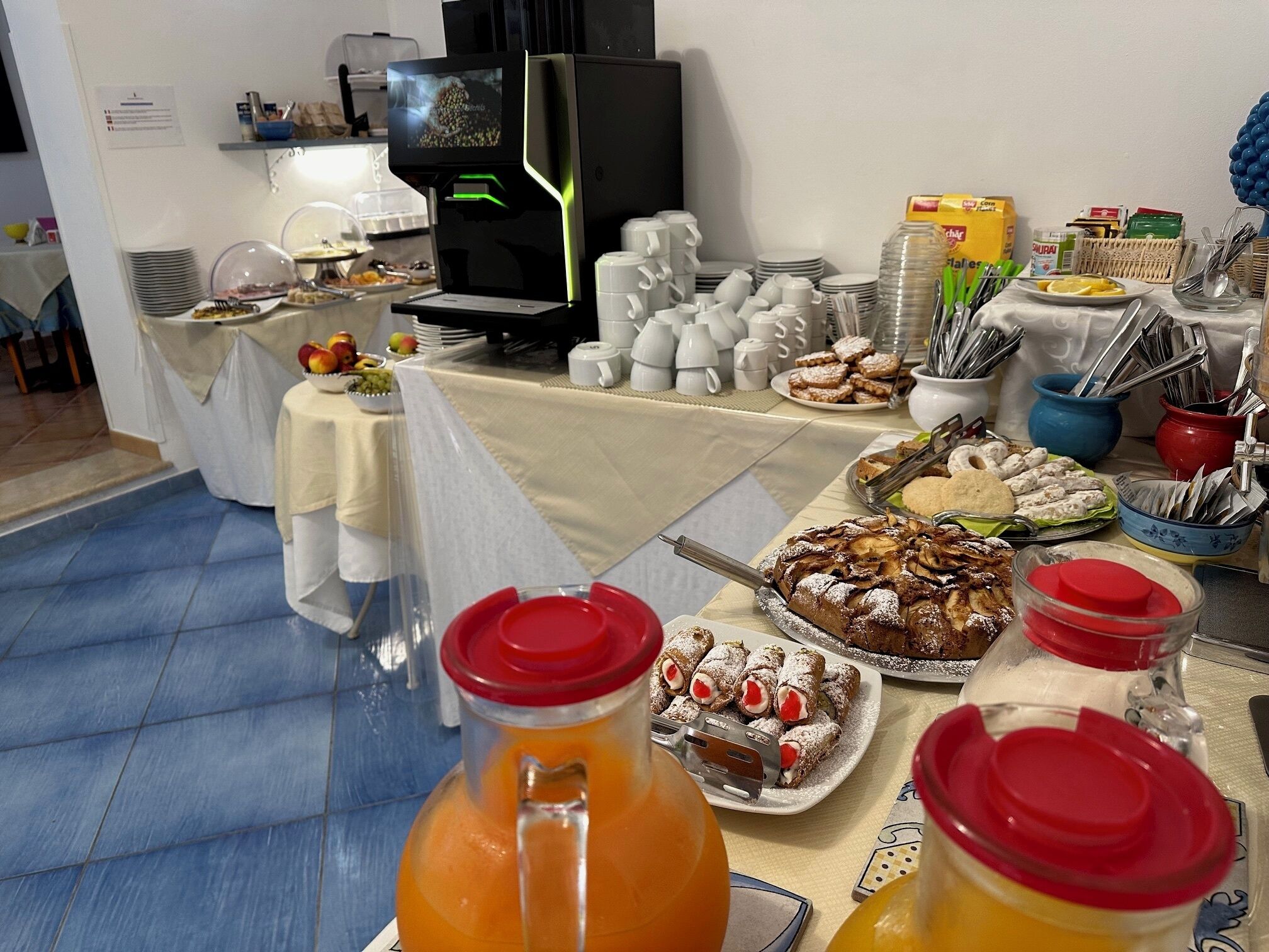 Uma mesa de buffet com diversos alimentos, incluindo bolo, frutas e bebidas.