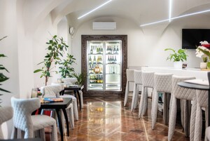 Um restaurante com área de bar, geladeira com bebidas e televisão na parede.