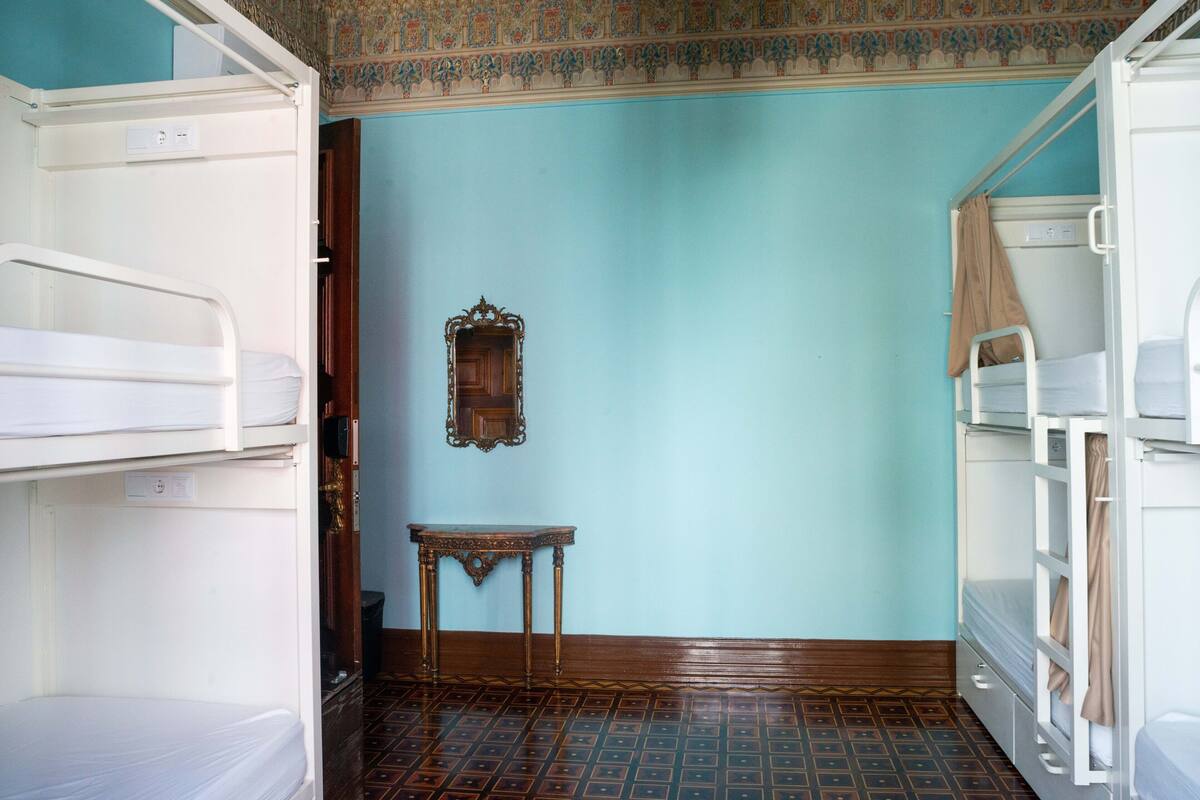 Um quarto com beliches, uma mesa de madeira e um espelho na parede.