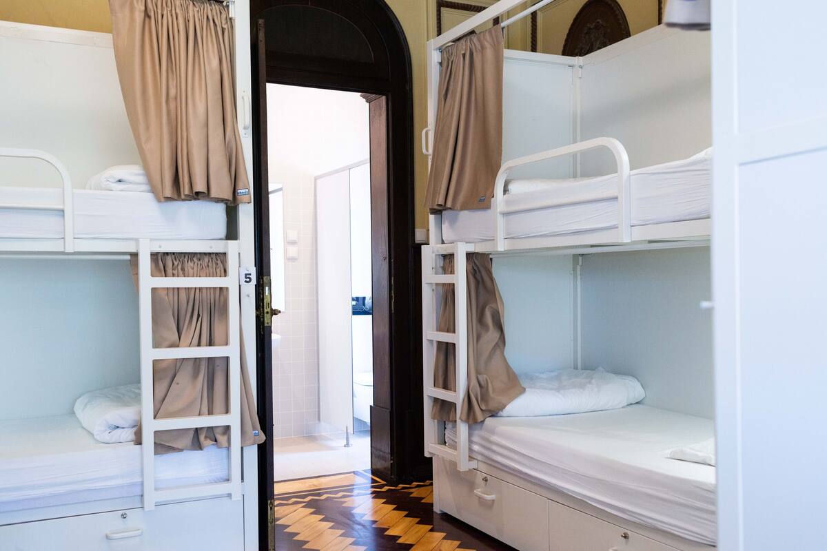 Um dormitório com duas camas, uma porta e um piso estampado.