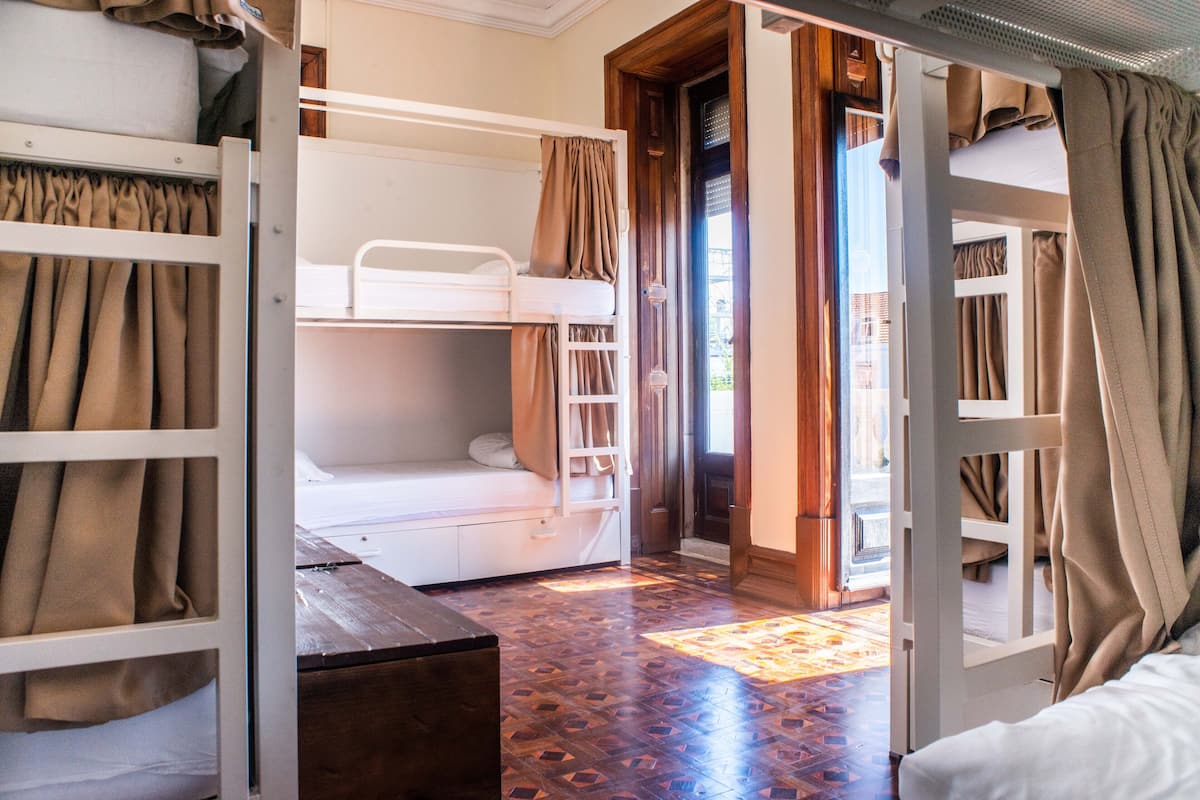 Quarto com beliches, piso de madeira e porta que dá para o exterior.