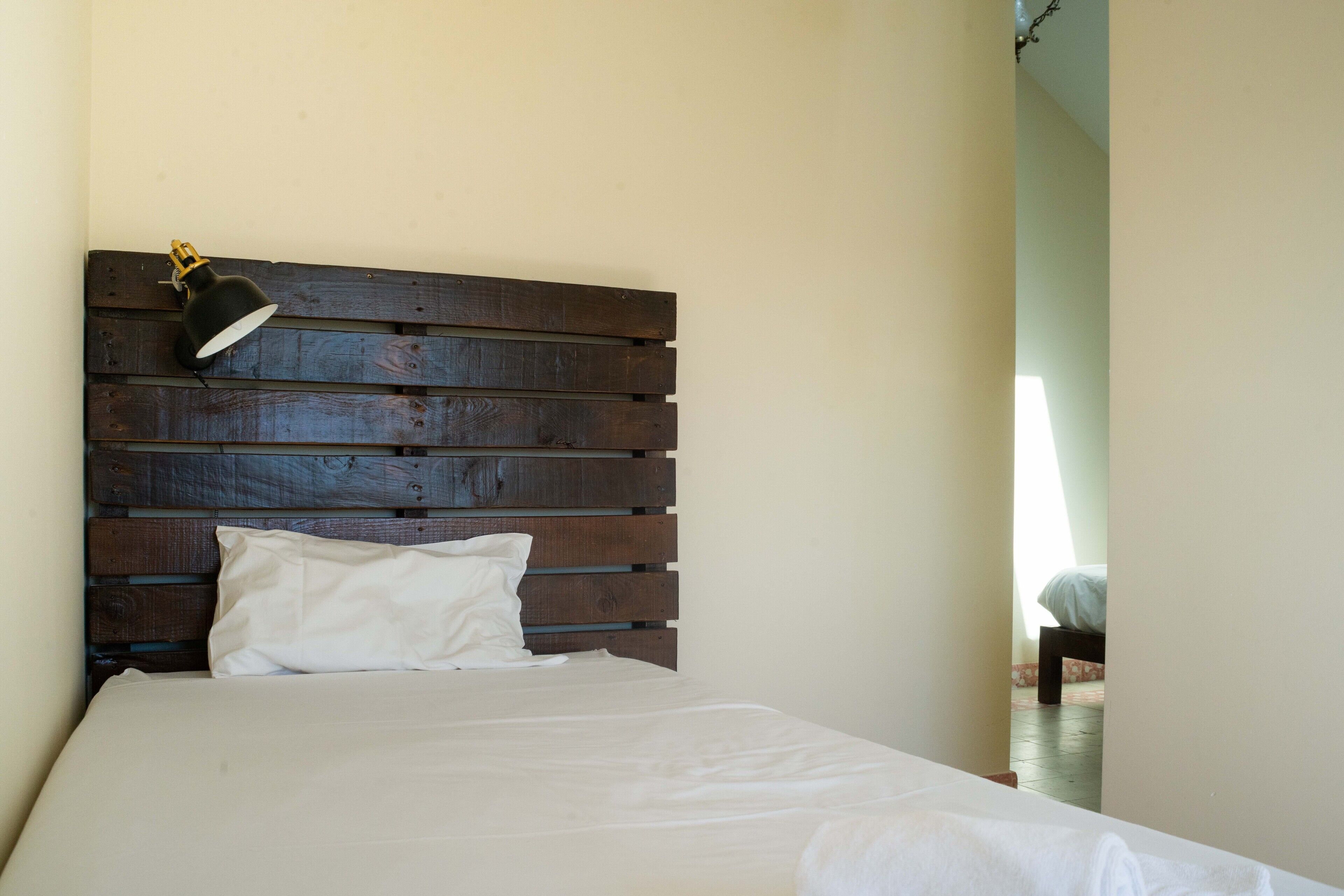 Cama com cabeceira de madeira e abajur.