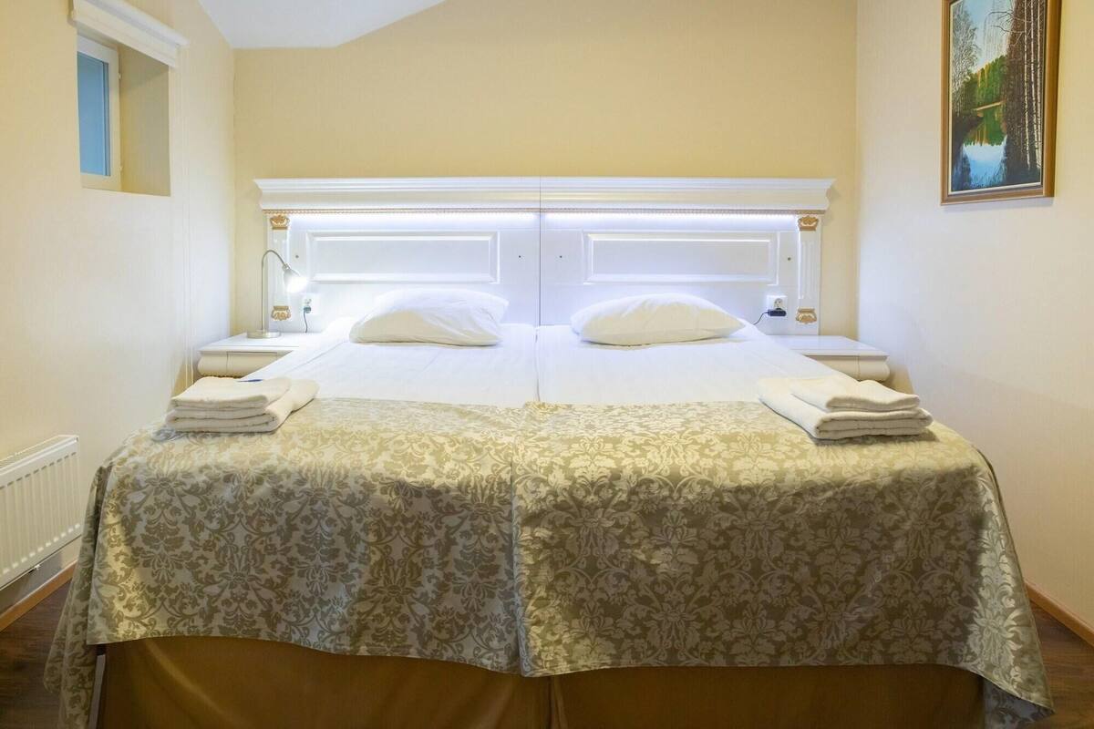 Uma cama de casal com cabeceira, mesas de cabeceira e um quadro na parede.