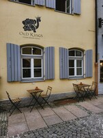 Um edifício com fachada amarela, duas janelas com persianas cinzentas e uma placa com a inscrição 'Old Kings FÜSSEN-Design Hostel'.