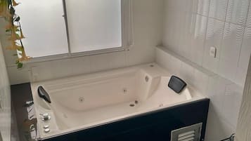 Um banheiro moderno com uma banheira independente, uma janela e um espaço com chuveiro.