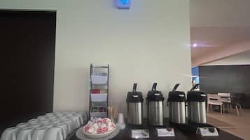 Estação de café com várias máquinas de café e uma bandeja de canecas.