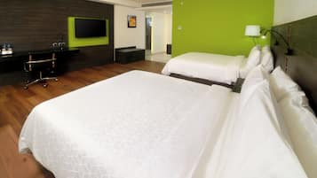 Quarto de hotel com uma cama grande, uma escrivaninha com cadeira, televisão e uma parede verde decorativa.