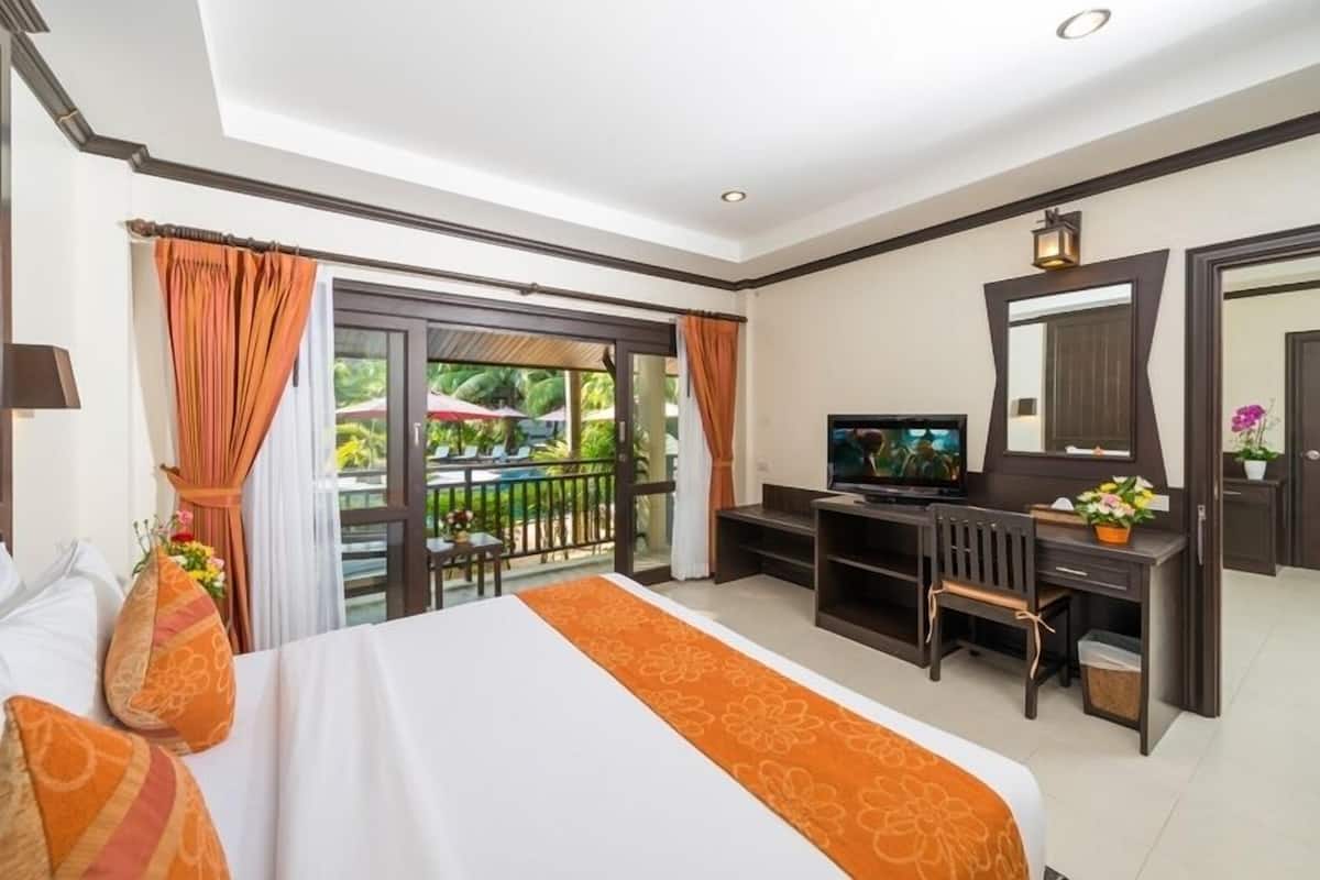 Quarto de hotel com cama, escrivaninha, televisão e varanda com vista para a piscina.