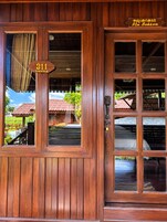 Uma porta de madeira com placa de número, uma janela e vista de um prédio com telhado vermelho.