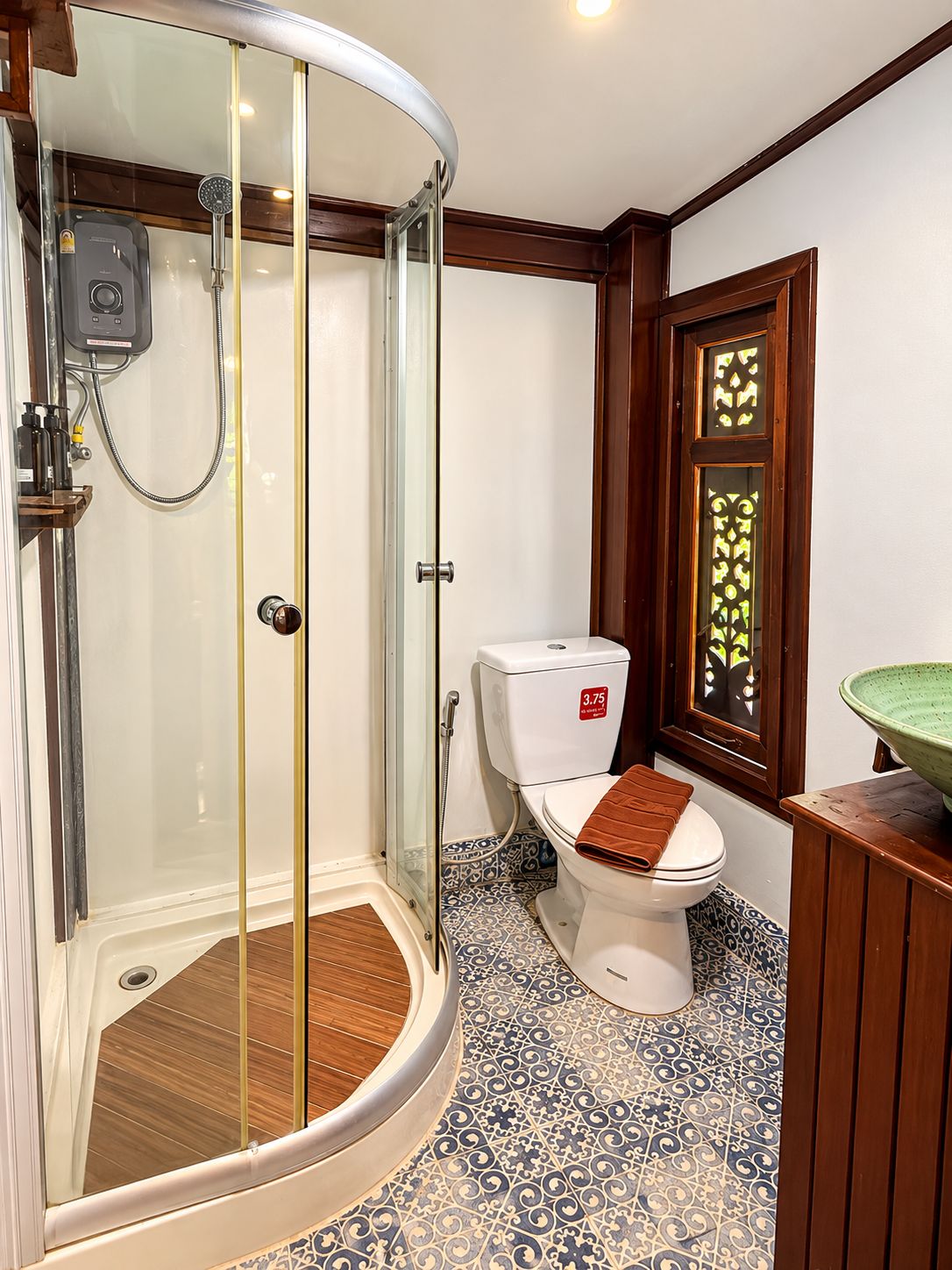Casa de banho com chuveiro em cabine de vidro, sanita com função bidé e lavatório com cuba verde.