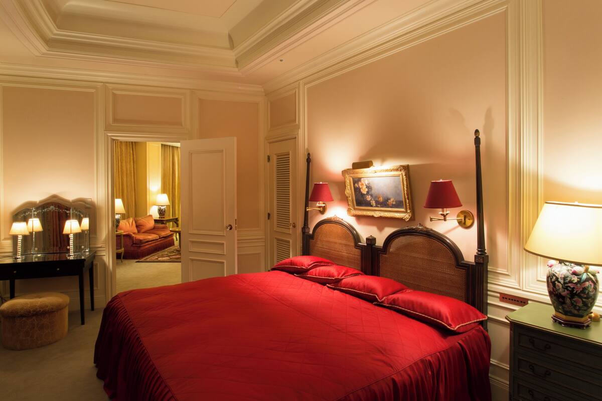 Quarto de hotel com uma cama grande, uma escrivaninha com luminárias, uma cadeira e uma cômoda.