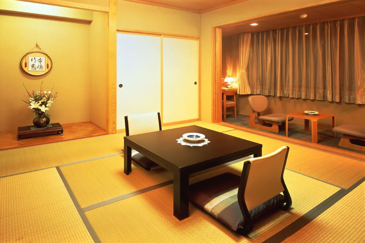 Um quarto japonês tradicional com tatames, uma mesa baixa e assentos.