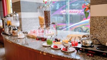 Balcão de recepção de hotel com diversos serviços, incluindo uma máquina de café, chaleira e exposição de bebidas coloridas.