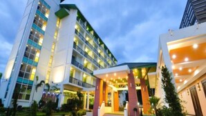 Um hotel com vários andares, uma entrada destacada, janelas amplas e fachada bem iluminada.