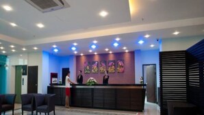 Uma área de recepção de hotel com design moderno, com balcão de atendimento, espaço para sentar e obras de arte na parede.