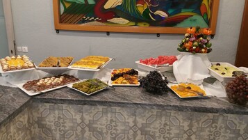 Mesa de buffet com diversos alimentos e um vaso decorativo com flores.