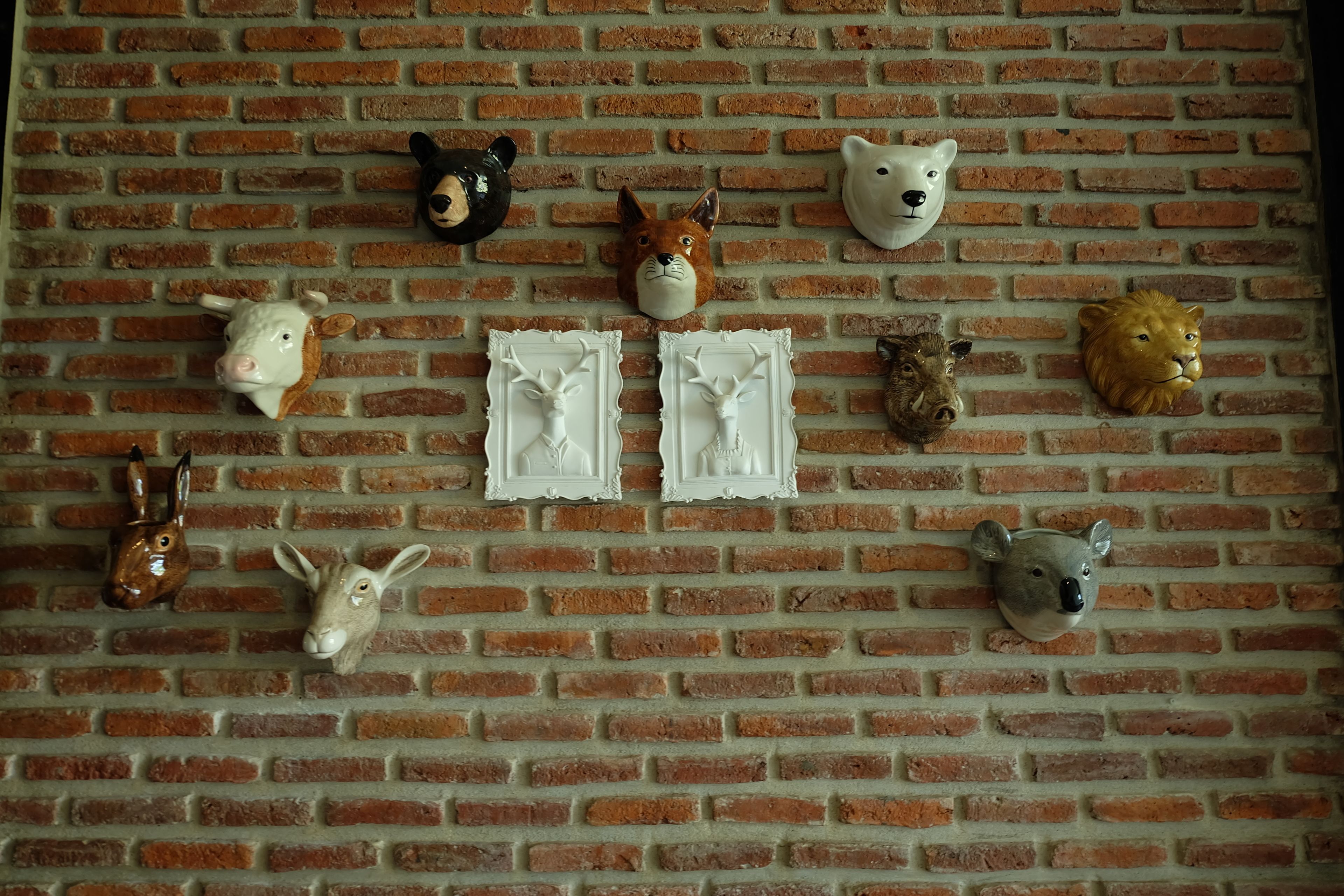 Uma parede de tijolos com diversas esculturas de cabeças de animais.