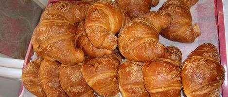 Uma bandeja com croissants dourados e cor de castanho sobre uma bandeja branca com borda rosa.
