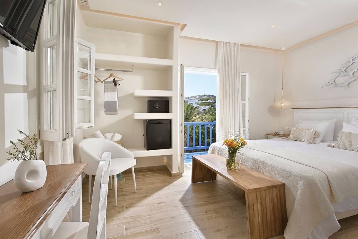 Quarto moderno com uma cama grande, uma escrivaninha e vista para o exterior.