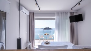 Quarto de hotel com uma cama, uma mesa com um chapéu e vista para o mar.