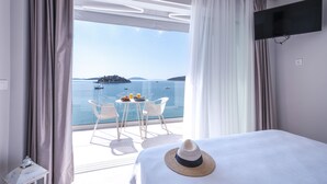 Quarto de hotel com varanda, uma cama com um chapéu e uma mesa com bebidas e um prato.
