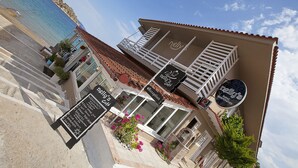 Um hotel com área de recepção, uma varanda com grades brancas e uma placa indicando que é um hotel com apartamentos.