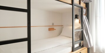 Uma cama beliche com cabeceira de madeira e uma pequena prateleira.